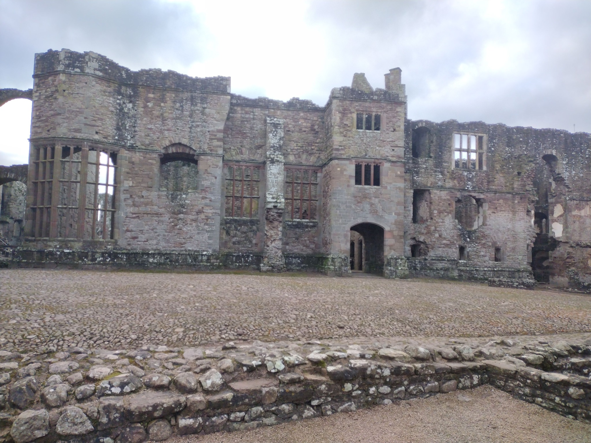 Le côté ouest de la cour en pierre inclinée, avec le hall et son oriel ...